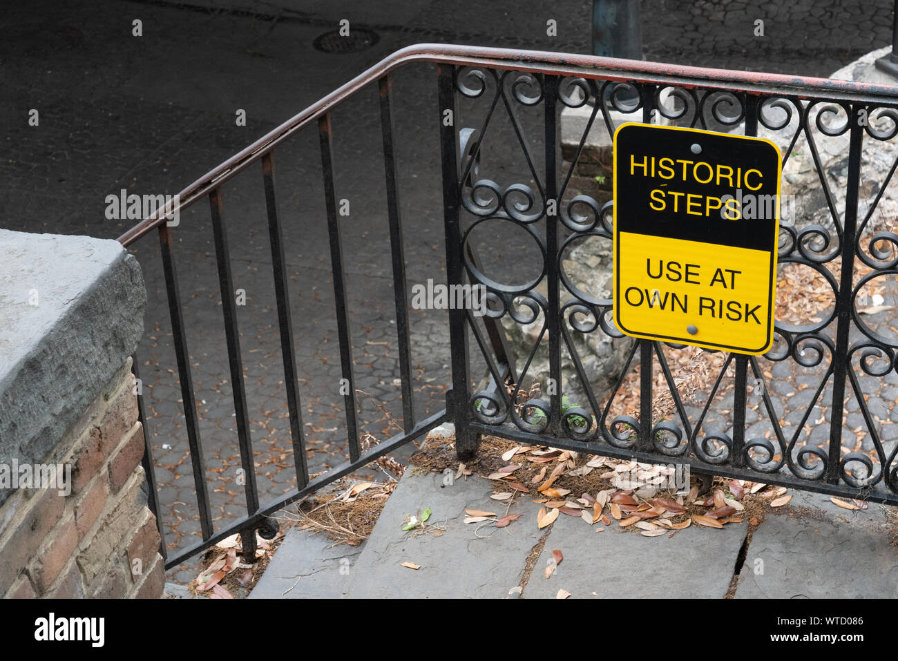 Yellow and black Historic steps use at own risk sign on wrought iron ...