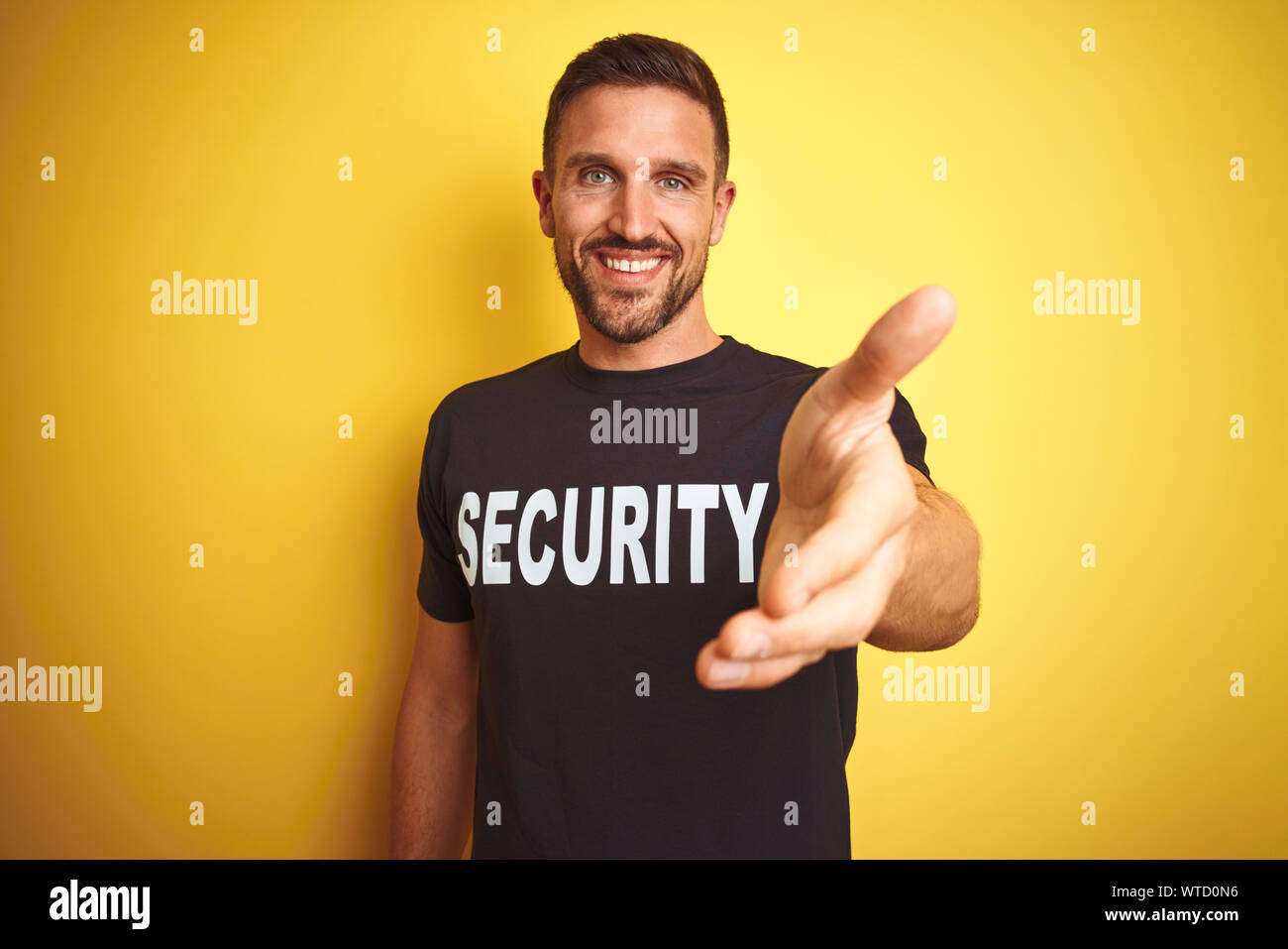 Young safeguard man wearing security uniform over yellow isolated ...