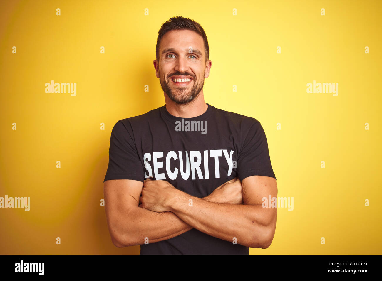 Young safeguard man wearing security uniform over yellow isolated ...