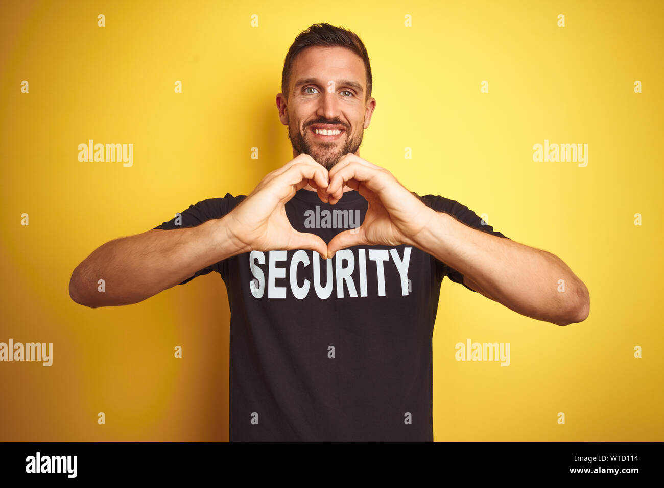 Young safeguard man wearing security uniform over yellow isolated ...