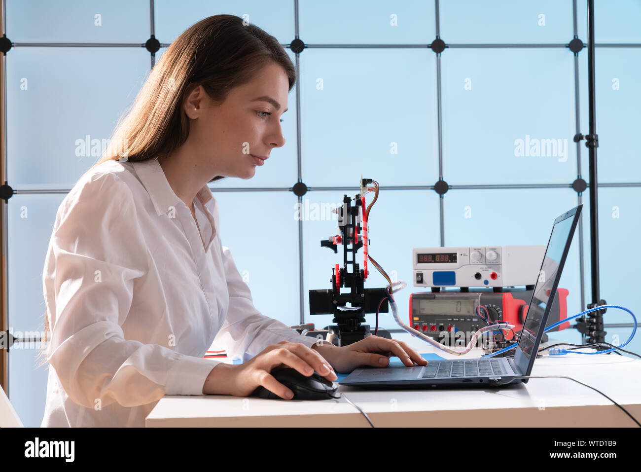 A young woman writes an algorithm for the robot arm. Science Research ...