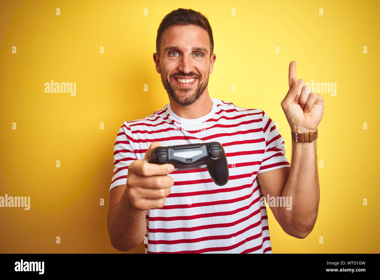 Young handsome man playing video games using joystick game pad over ...