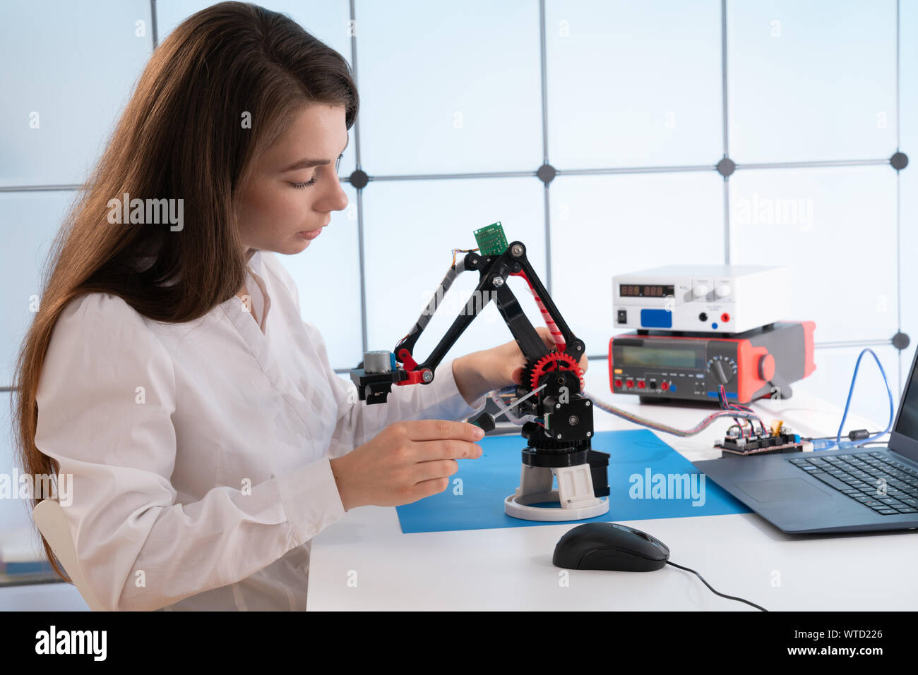 A young woman writes an algorithm for the robot arm. Science Research ...