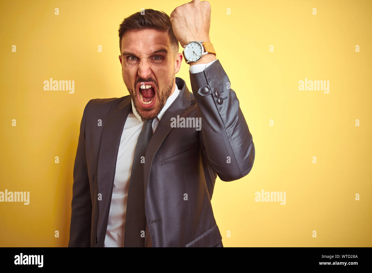 Young handsome business man over yellow isolated background angry and ...