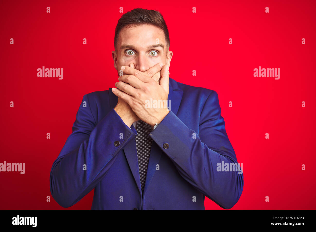 Young handsome business man over red isolated background shocked covering mouth with hands for ...