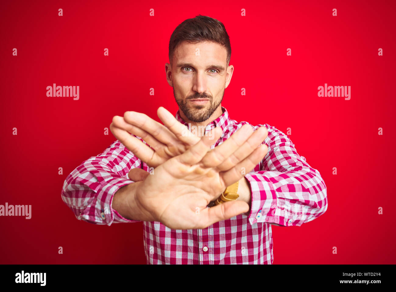 Young handsome man over red isolated background Rejection expression ...