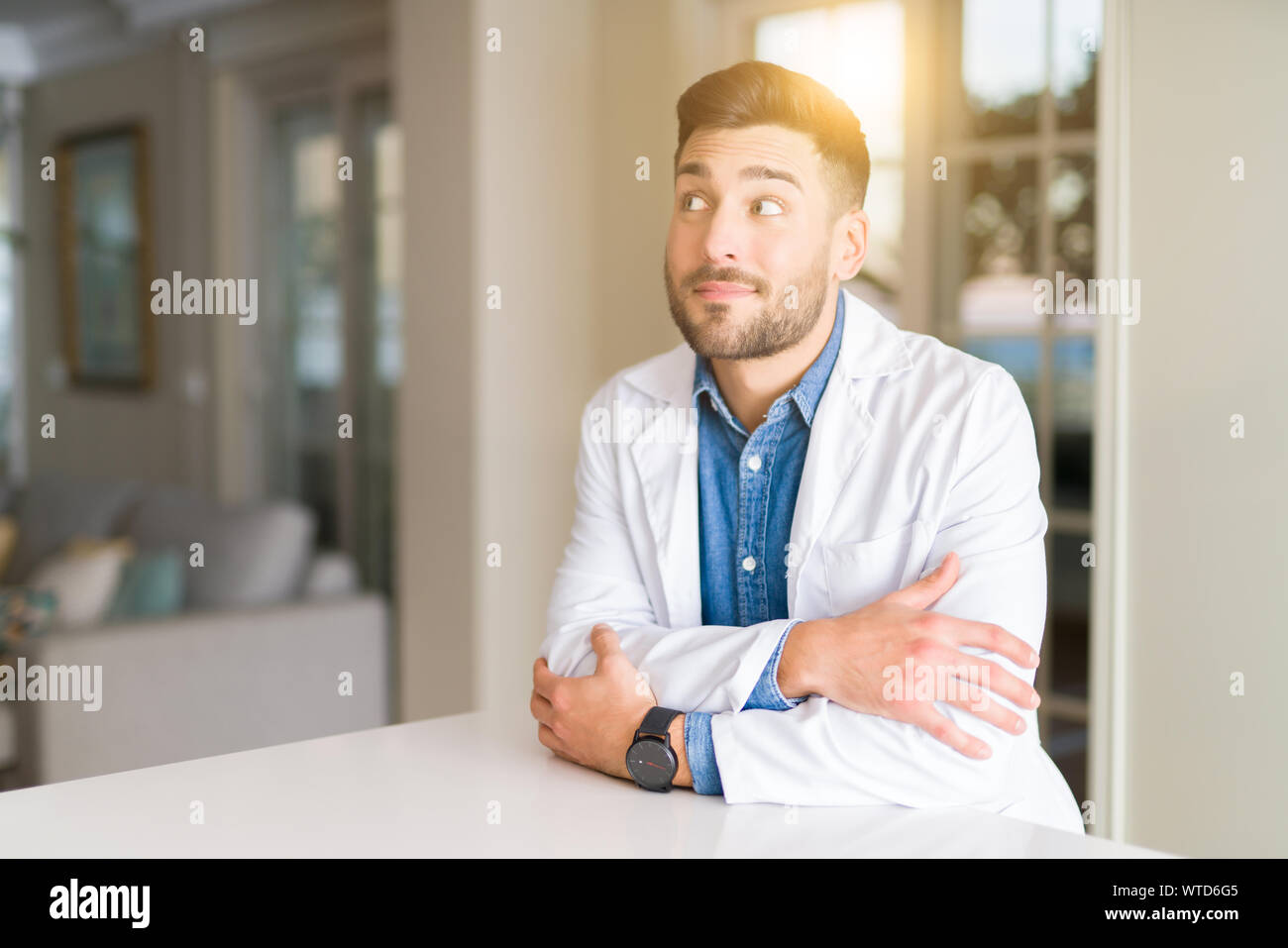 Young handsome doctor man at the clinic smiling looking side and ...