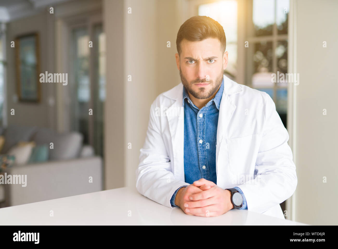 Young handsome doctor man at the clinic skeptic and nervous, frowning ...