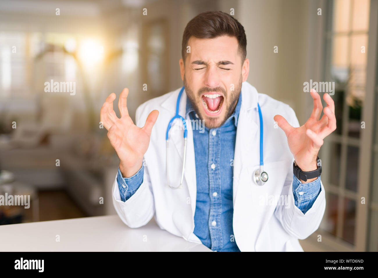 Young handsome doctor man at the clinic celebrating mad and crazy for ...