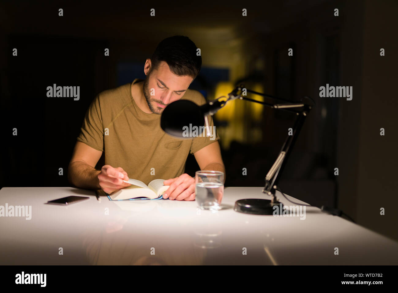 Young handsome man studying at home, reading a book at night Stock ...