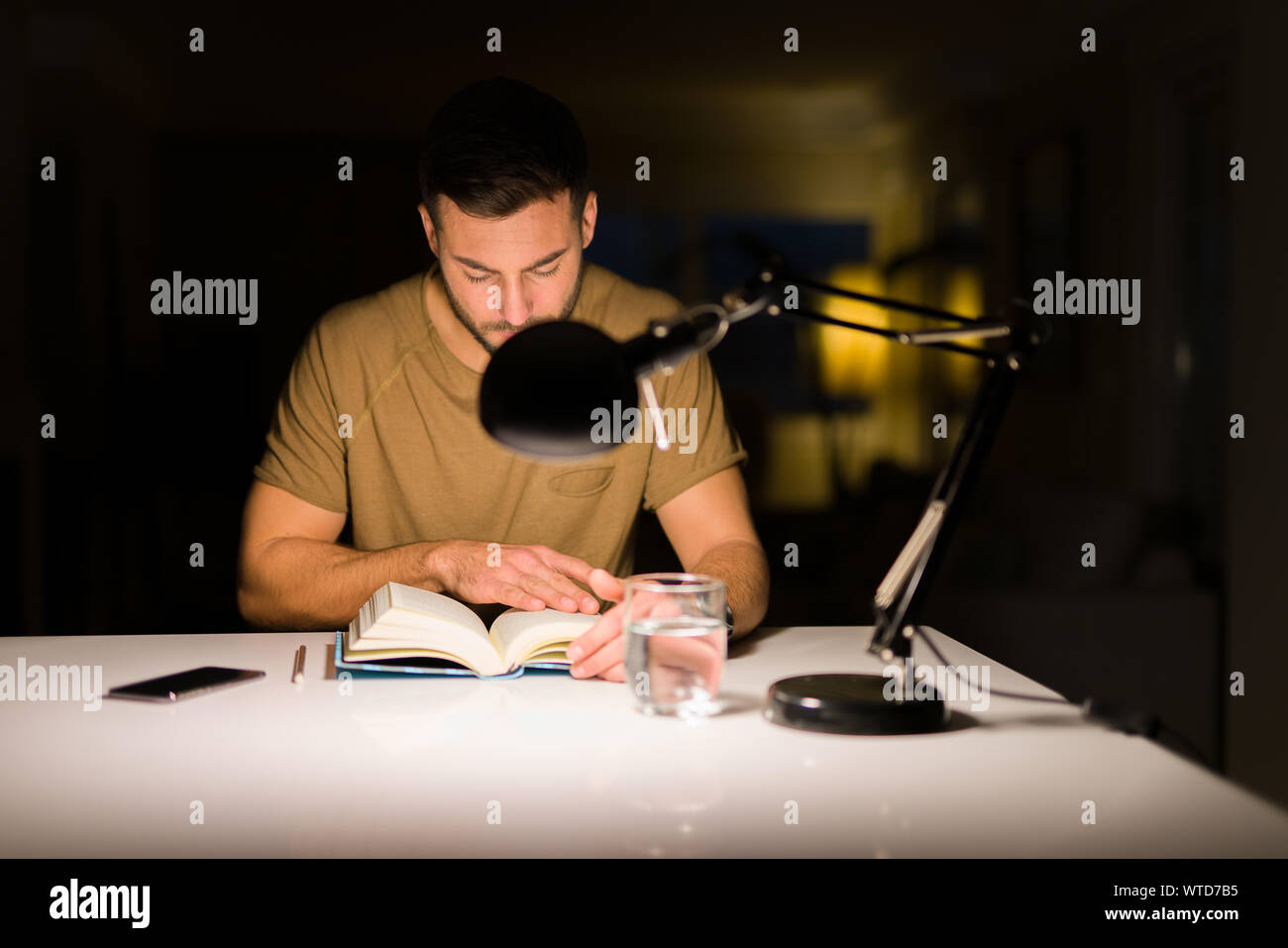 Young handsome man studying at home, reading a book at night Stock ...