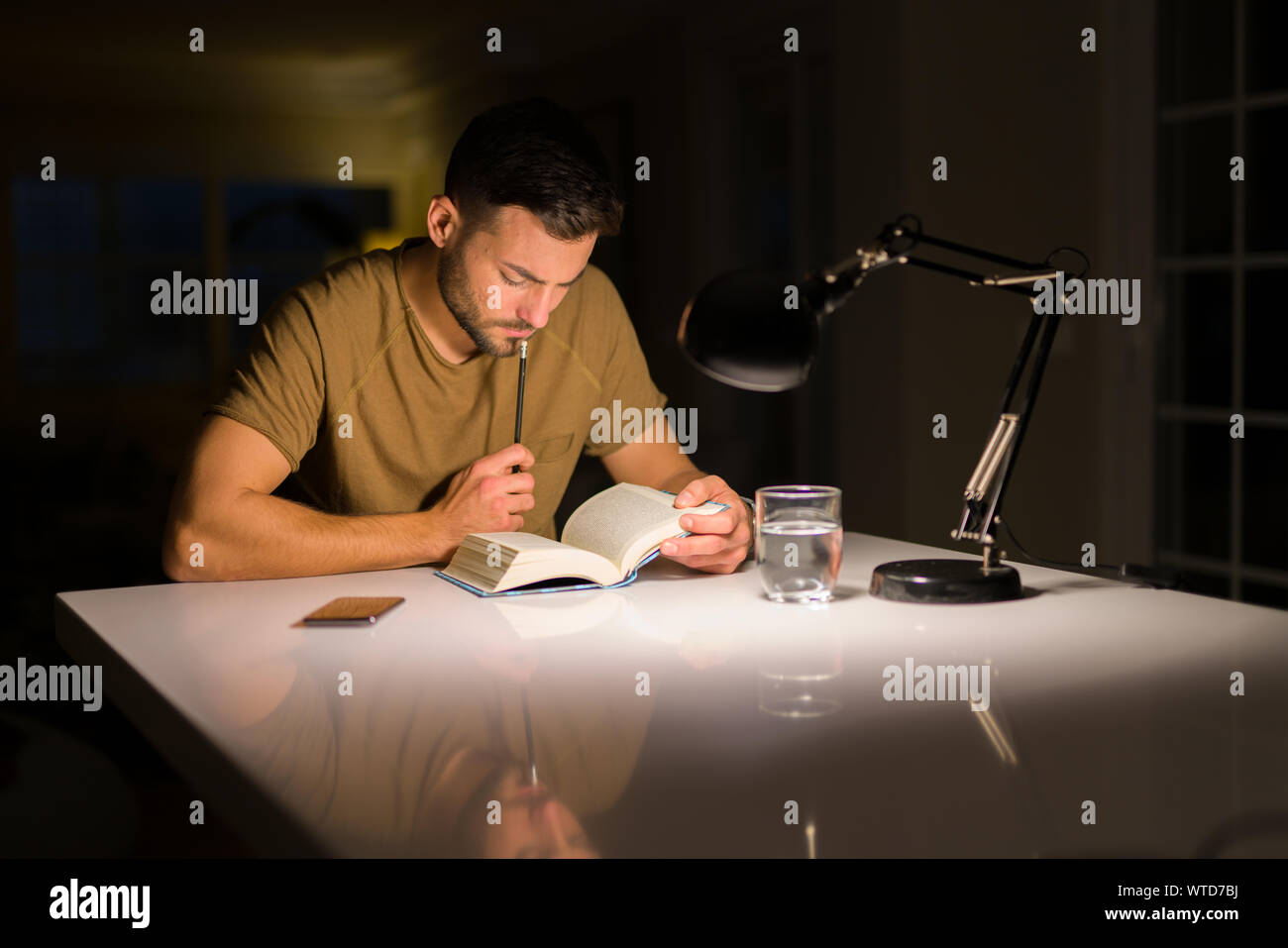 Young handsome man studying at home, reading a book at night Stock ...
