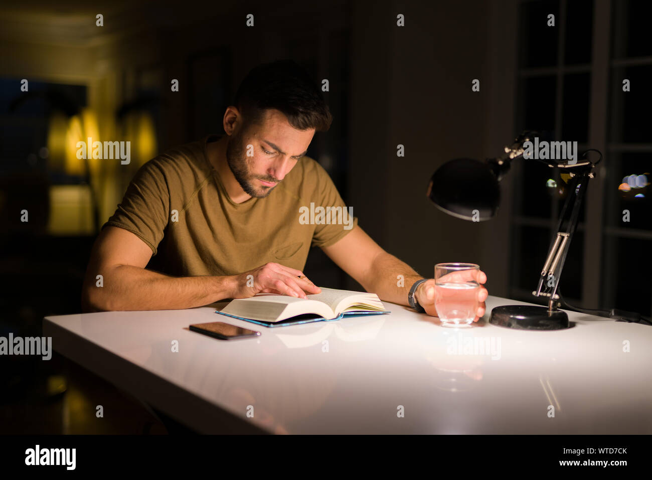 Young handsome man studying at home, reading a book at night Stock ...