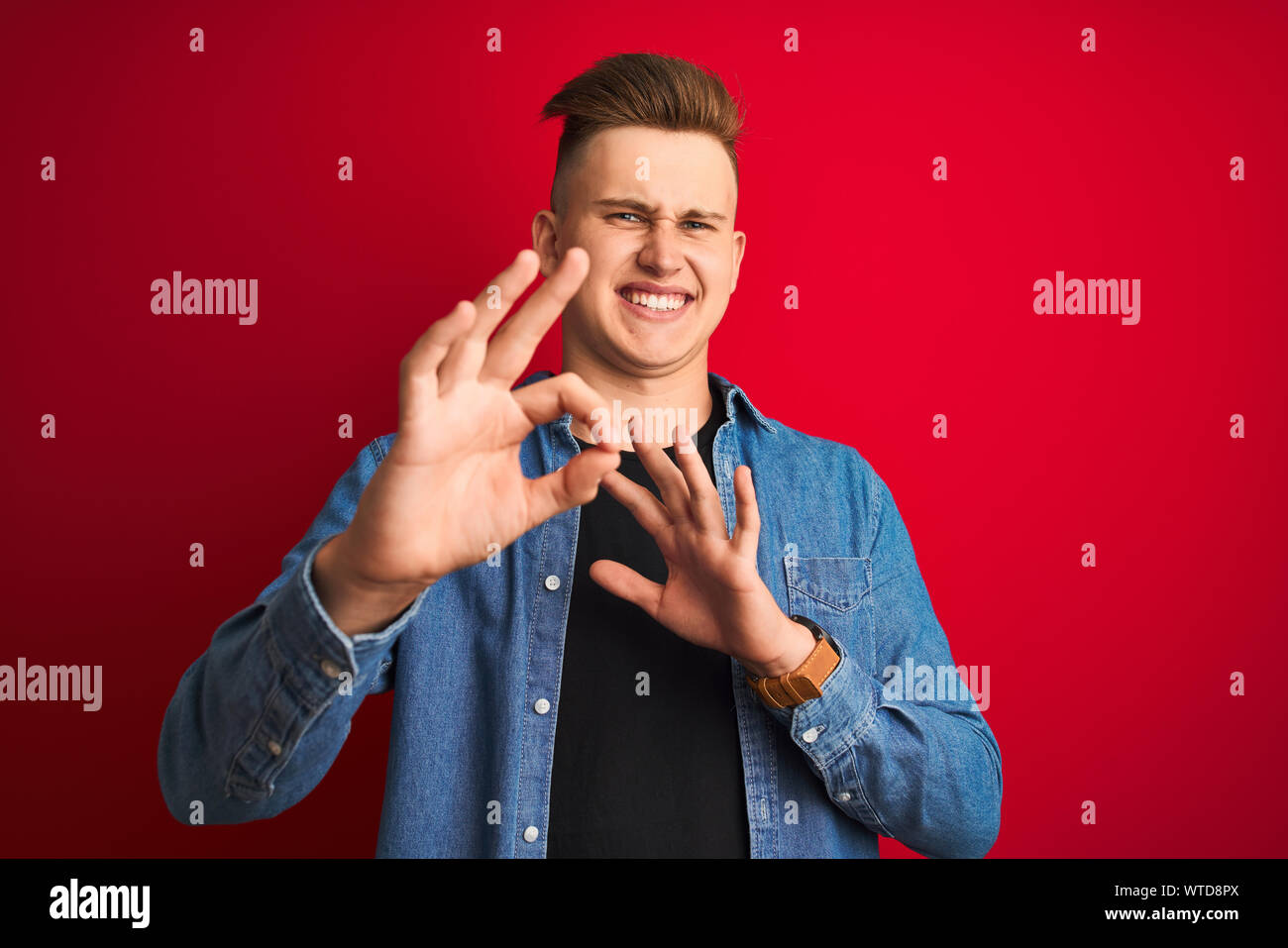 Young handsome man wearing denim shirt standing over isolated red ...