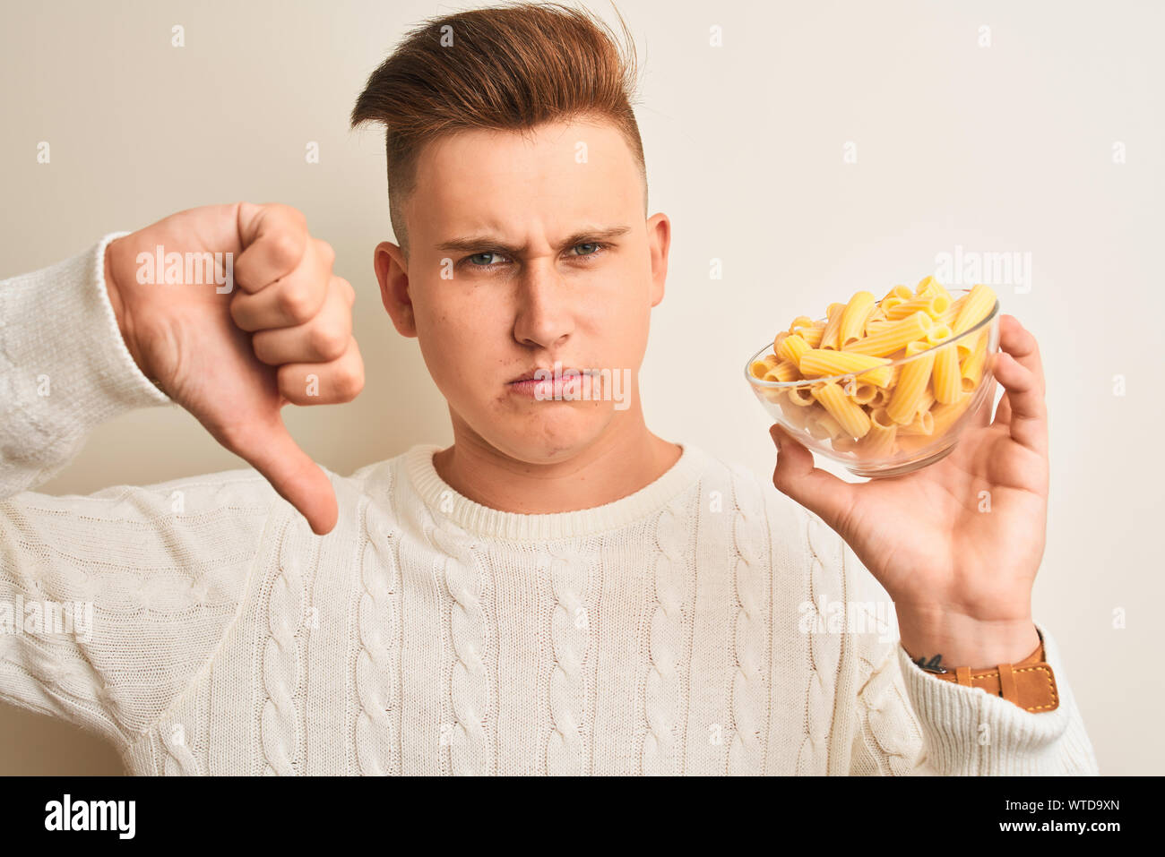 Young handsome man holding bowl with dry pasta standing over isolated ...
