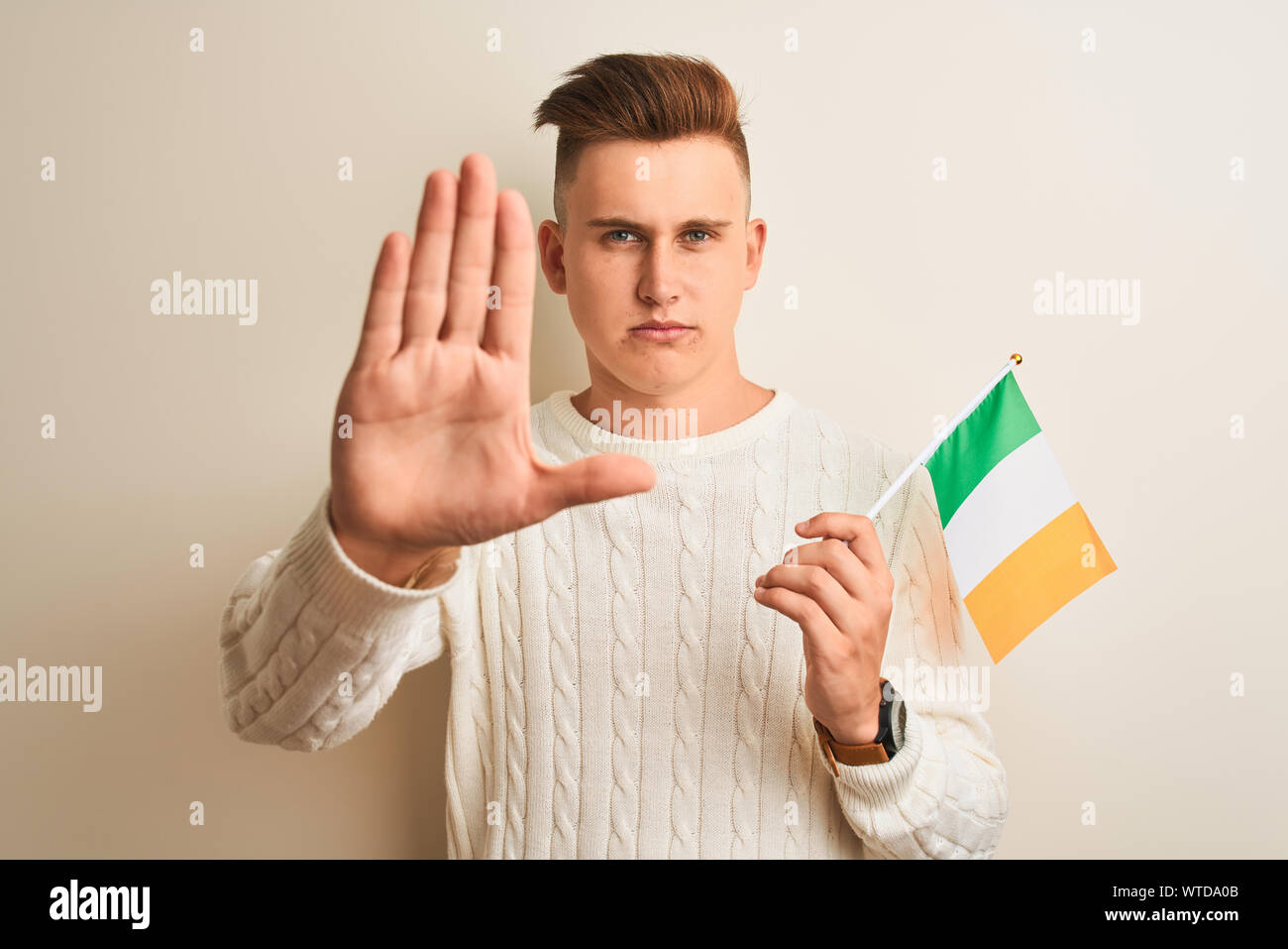 Young handsome man holding Ireland Irish flag over isolated white ...