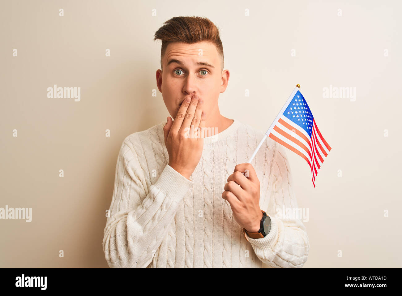 Young handsome man holding USA flag over isolated white background ...
