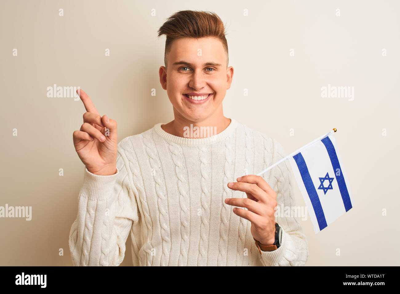 Young handsome man holding Israel Israeli flag over isolated white ...