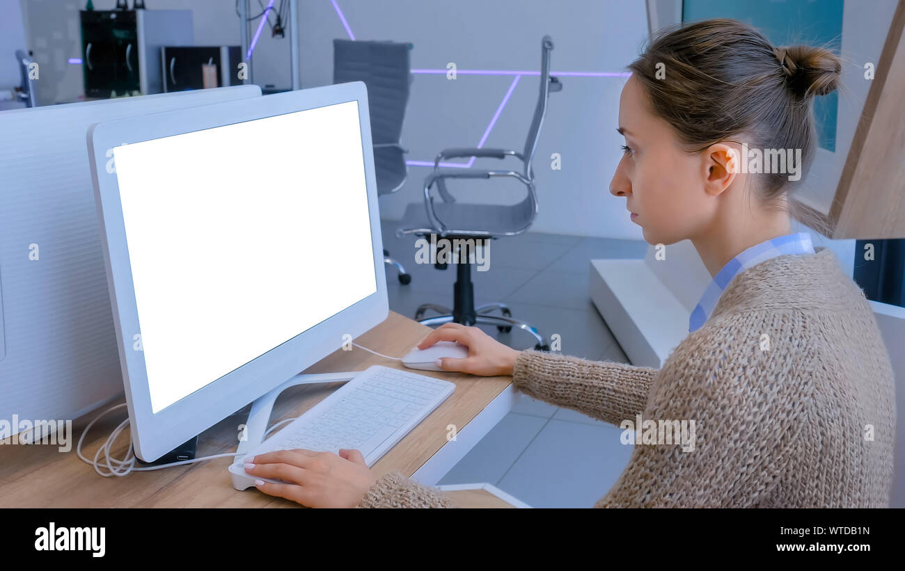 Woman looking at monitor of desktop computer with blank white display ...
