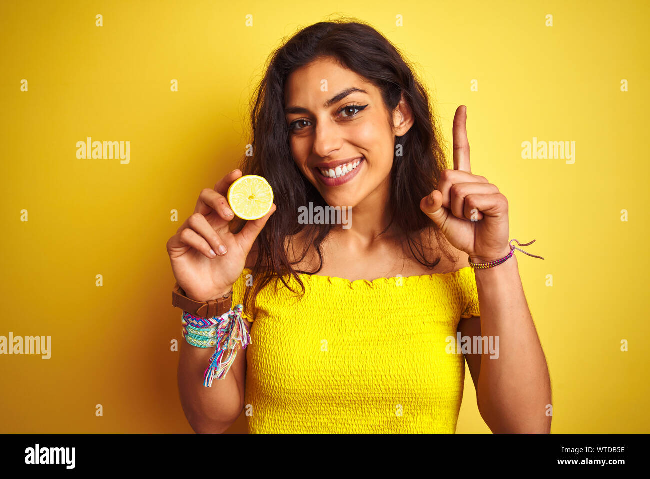 Young beautiful woman holding middle lemon standing over isolated ...