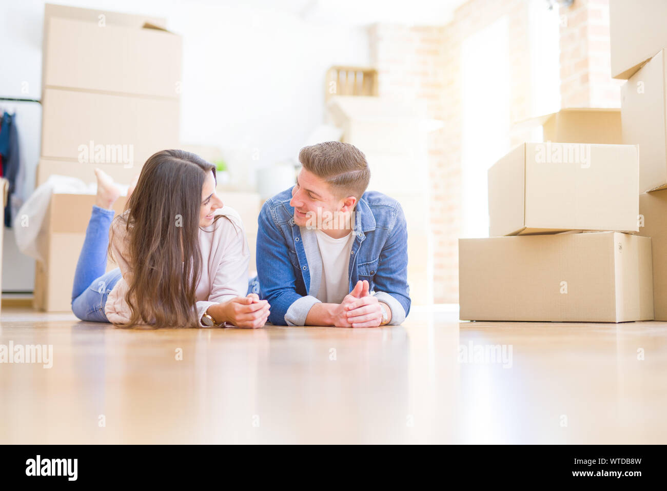Young beautiful couple relaxing lying on the floor around cardboard ...