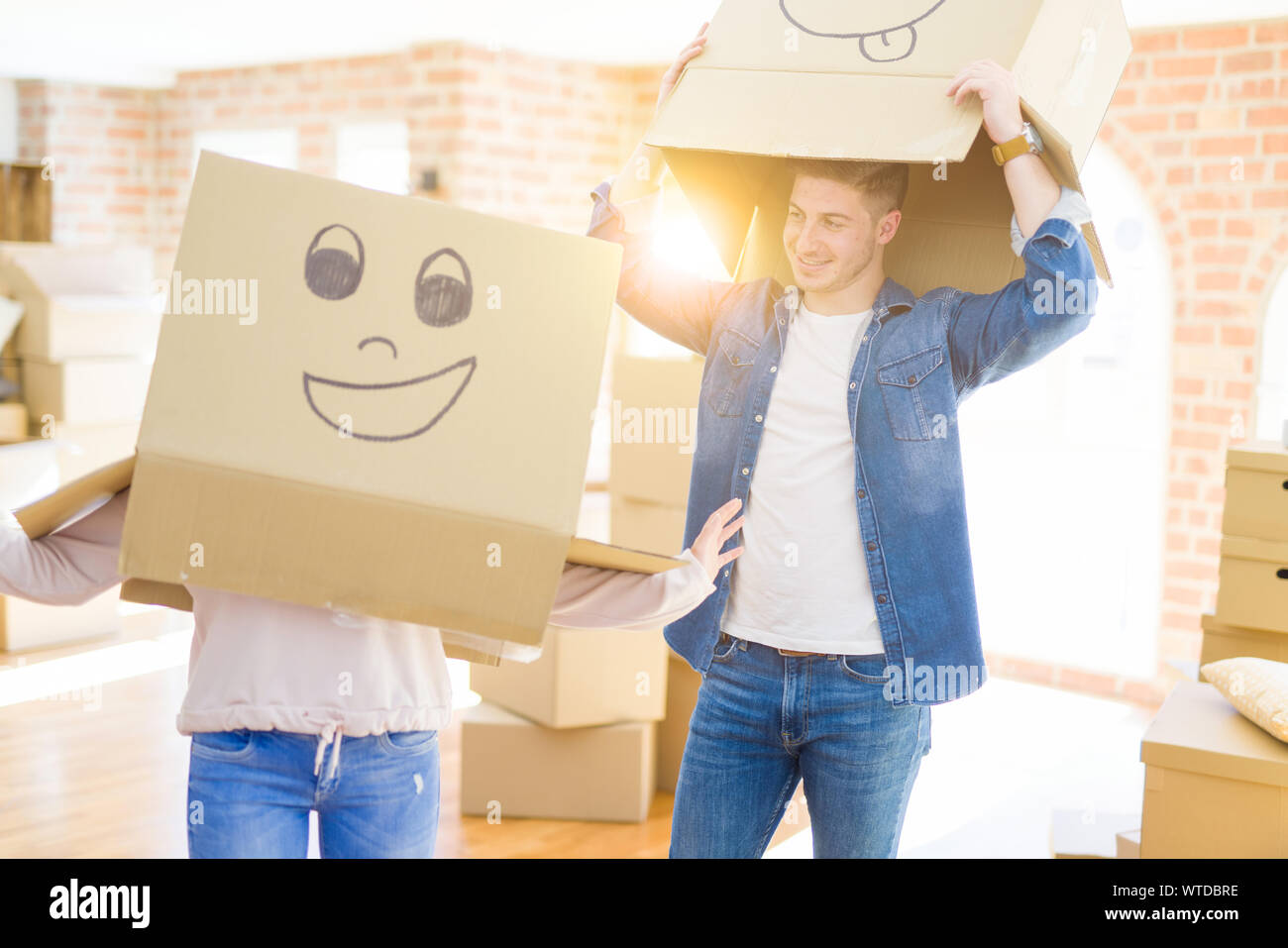 Couple having fun at new apartment wearing boxes with funny faces over ...