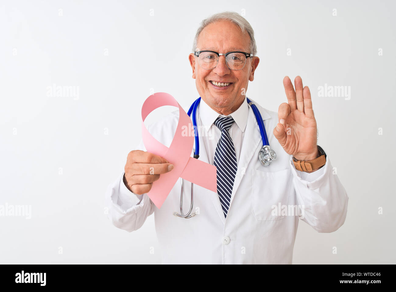 Senior grey-haired doctor man holding cancer ribbon over isolated white ...