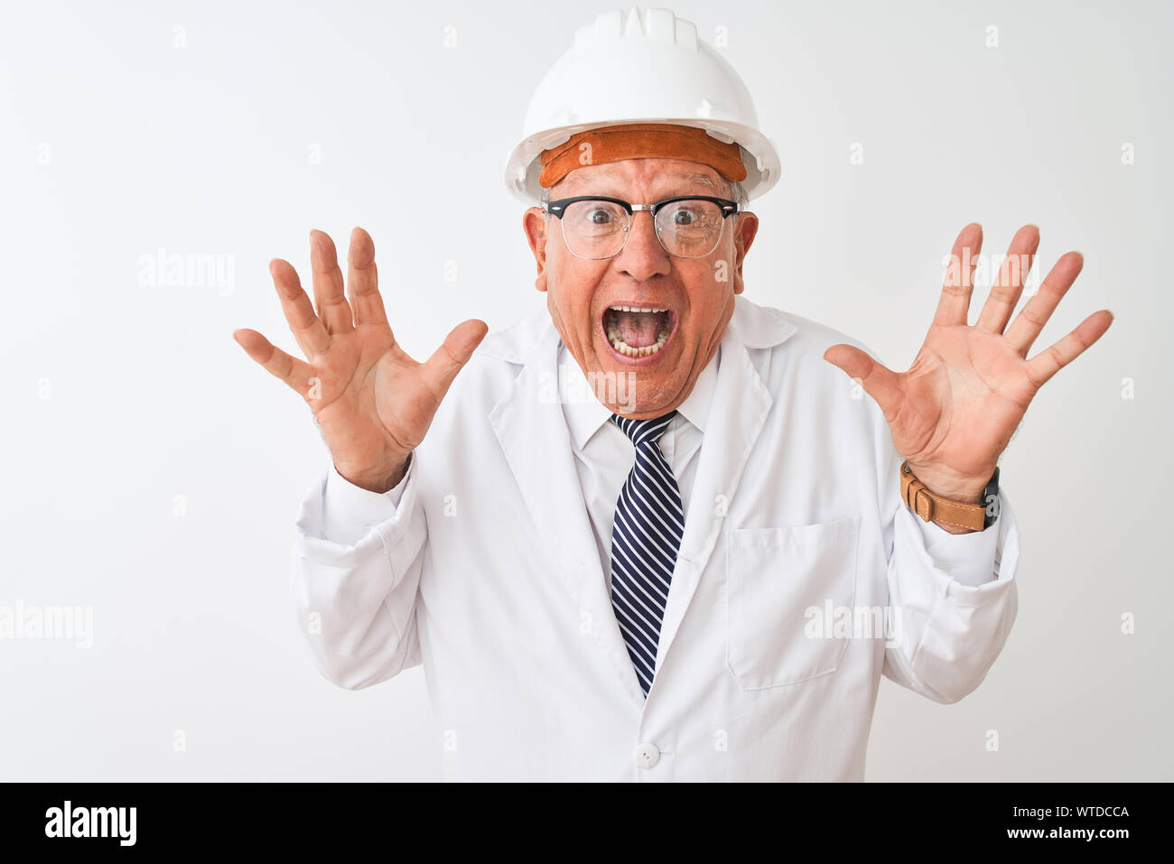 Senior grey-haired engineer man wearing coat and helmet over isolated ...