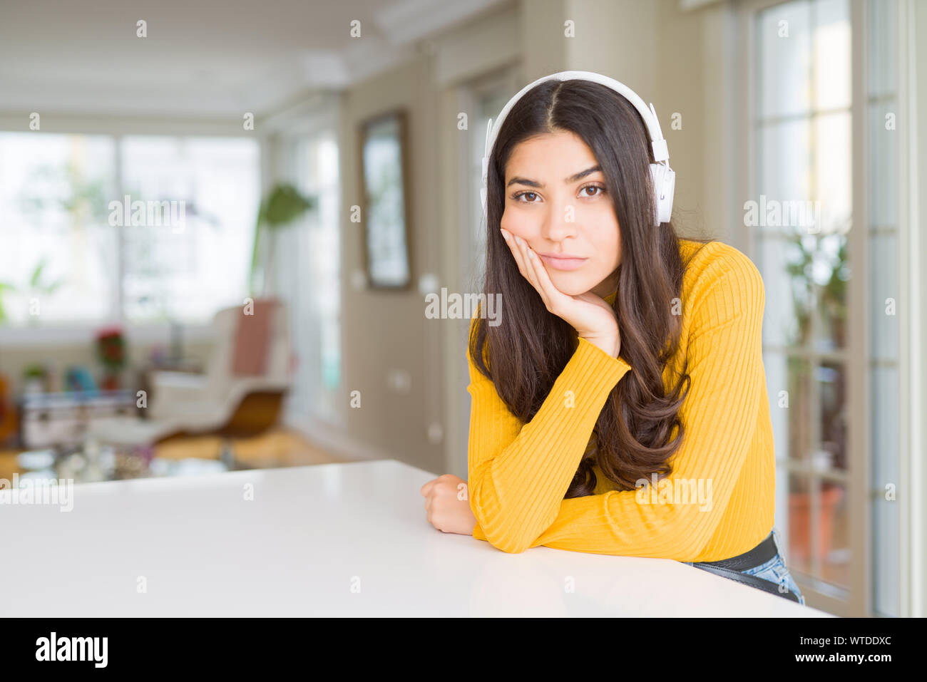 Young woman wearing headphones listening to music thinking looking ...