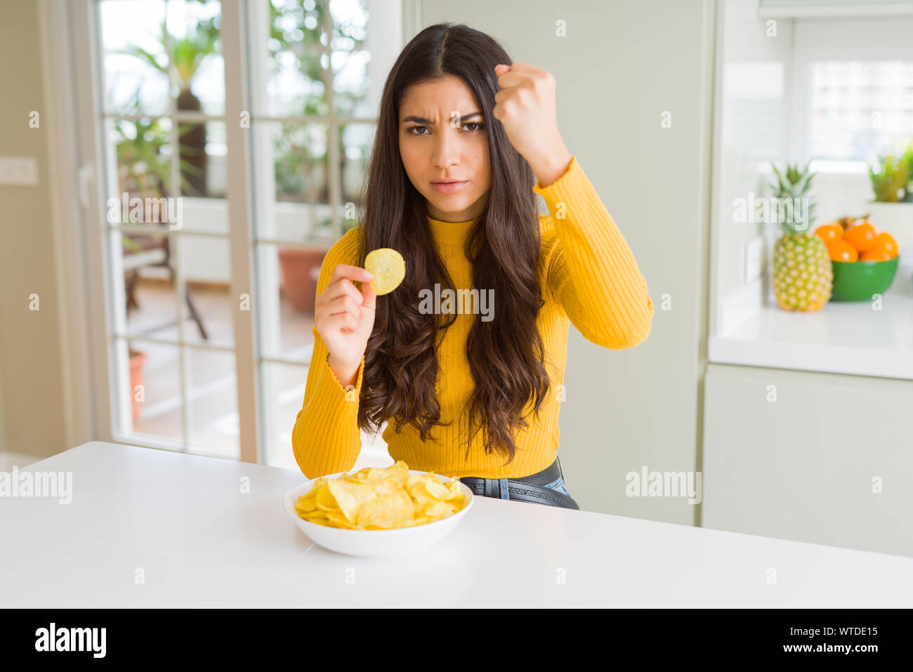Young woman eating fastfood potato chips annoyed and frustrated ...