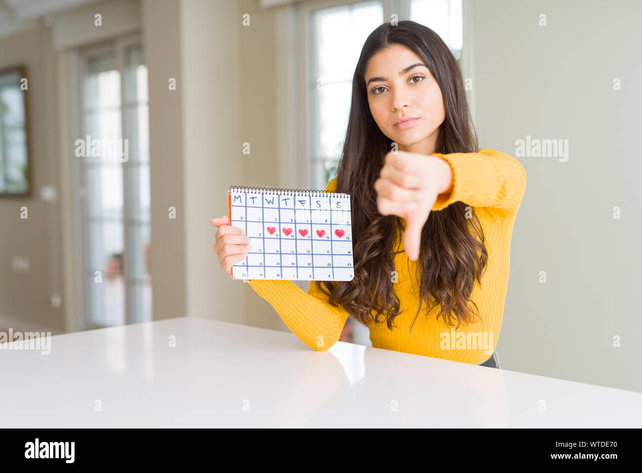 Young woman holding menstruation calendar with angry face, negative ...