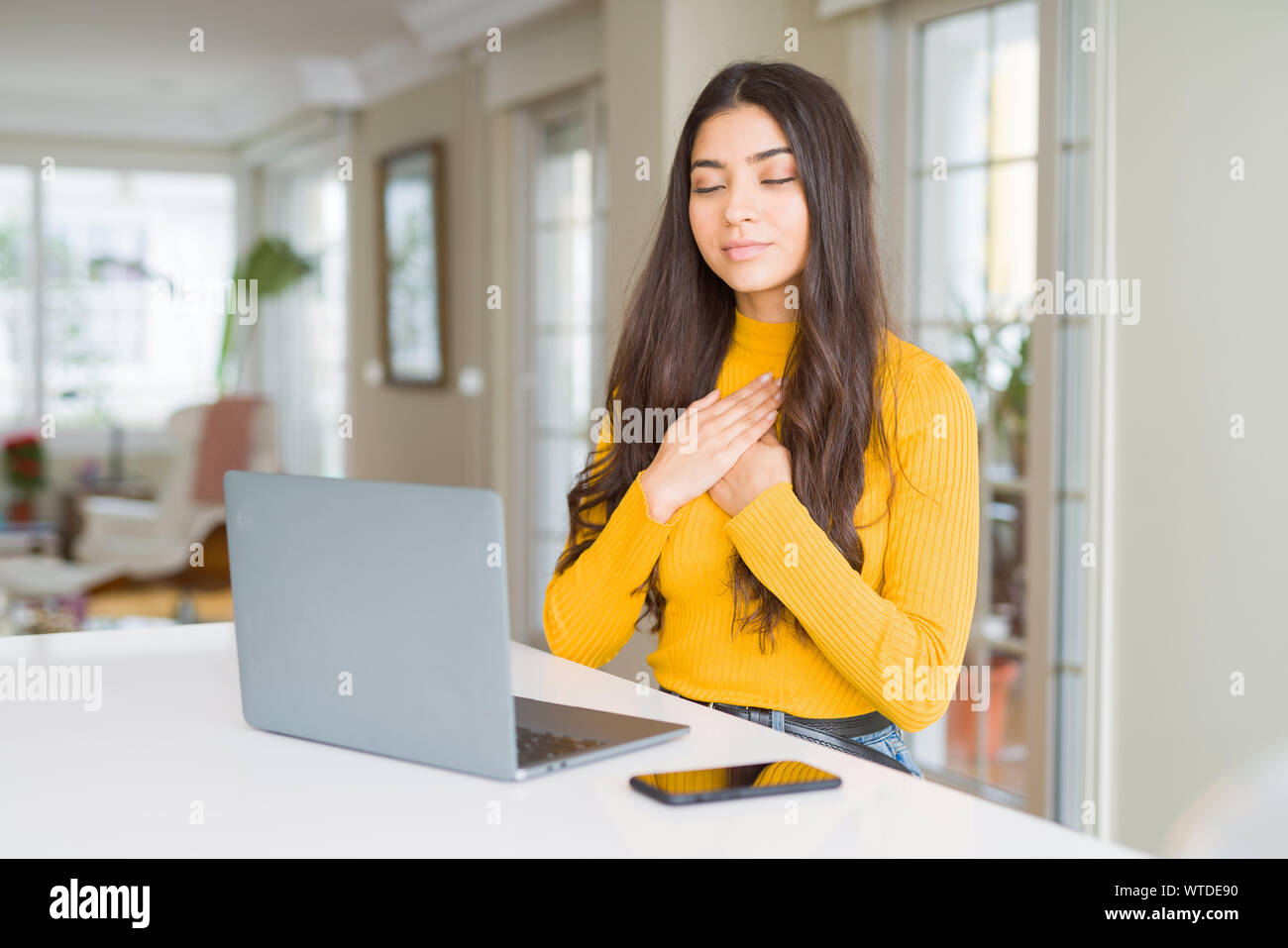 Young woman using computer laptop smiling with hands on chest with ...