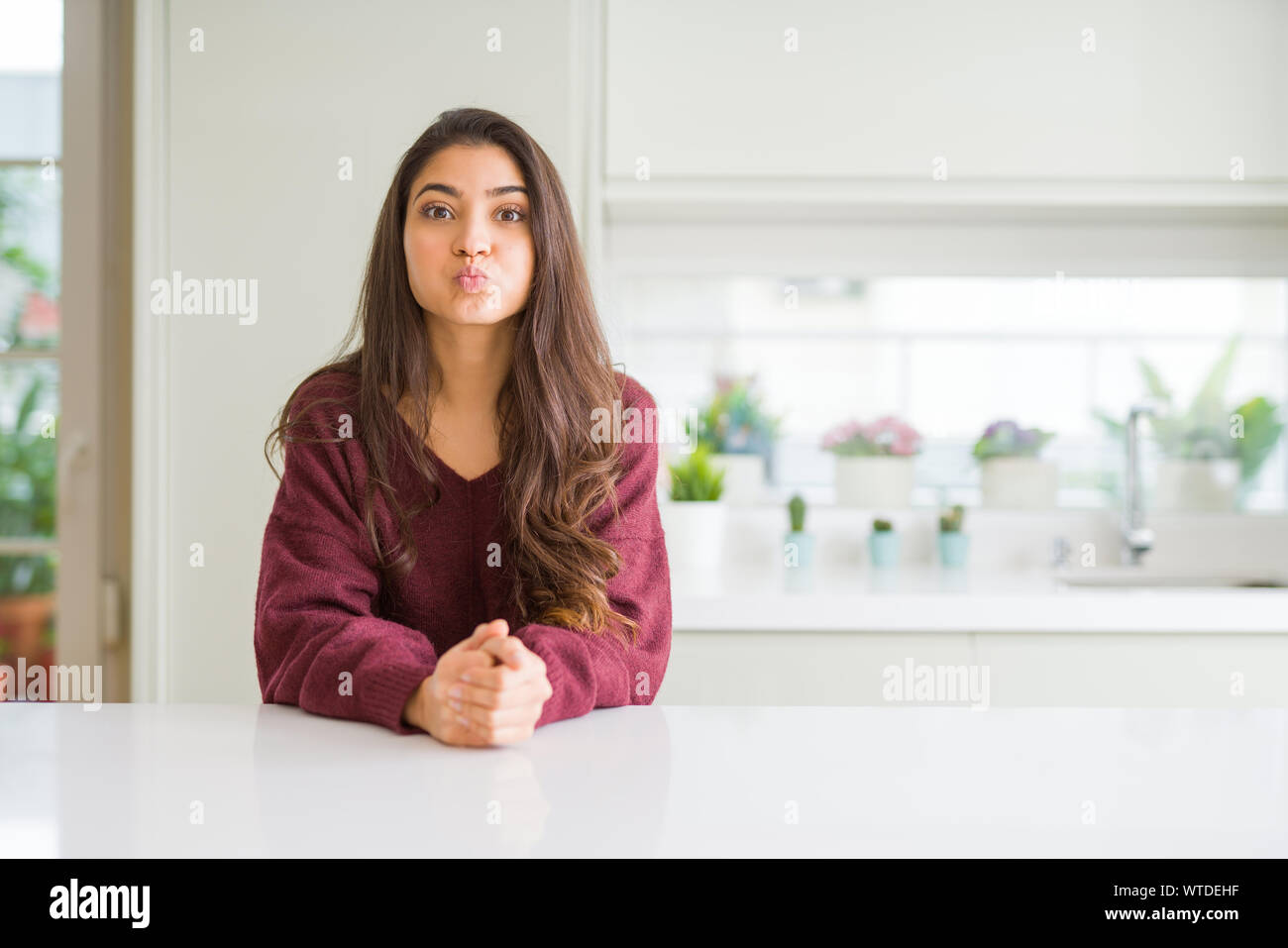 Young beautiful woman at home puffing cheeks with funny face. Mouth ...