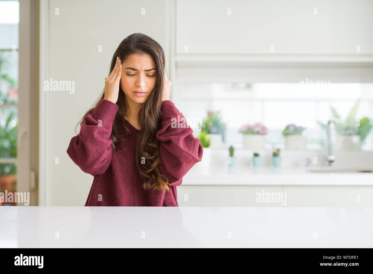 Young beautiful woman at home with hand on head for pain in head ...