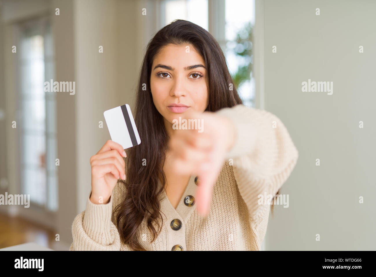 Young woman holding credit card as payment with angry face, negative ...