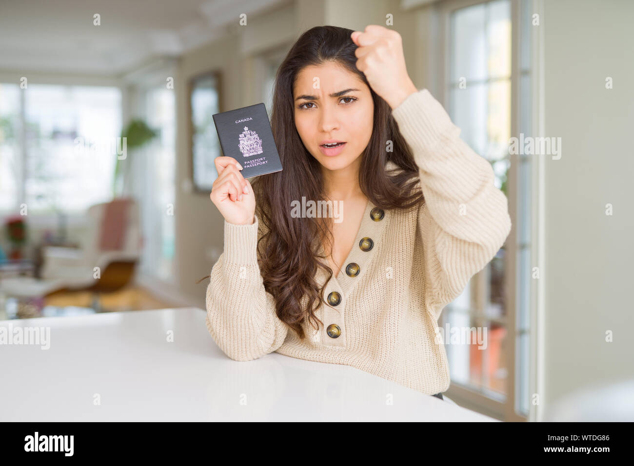 Young woman holding passport of Canada annoyed and frustrated shouting ...