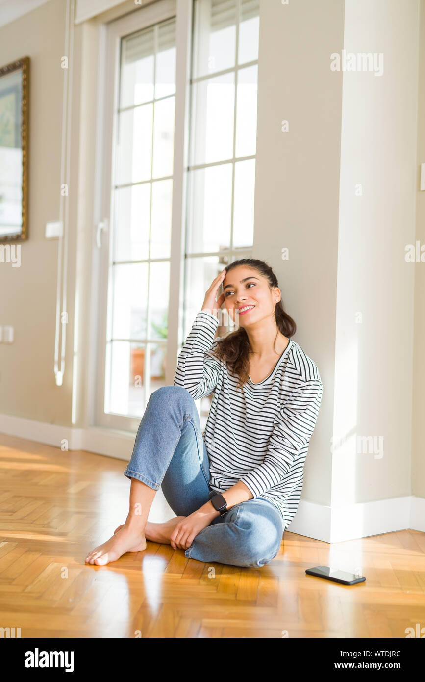 Young beautiful woman thinking and wondering with a hand on chin ...