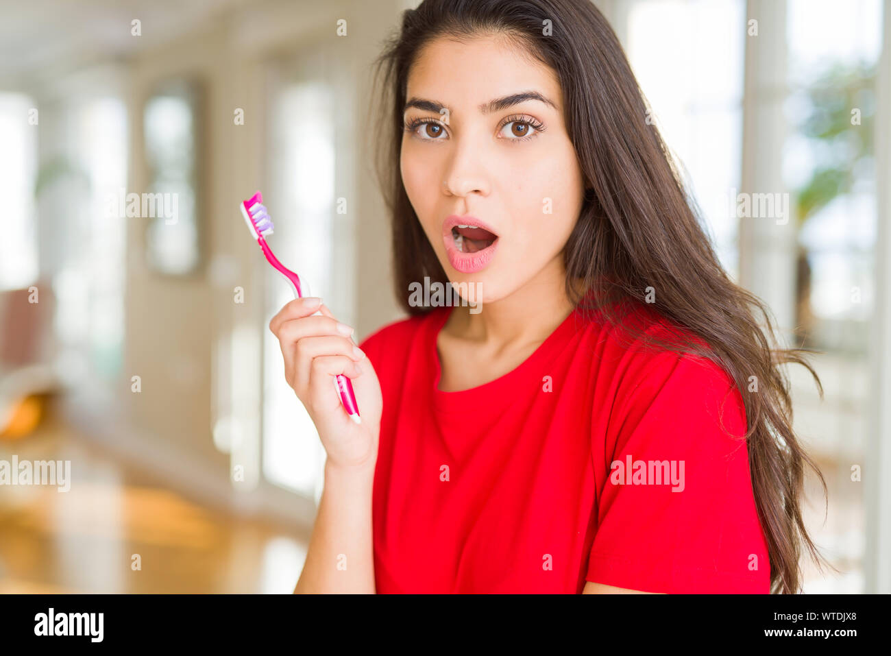 Young woman holding dental toothbrush scared in shock with a surprise ...