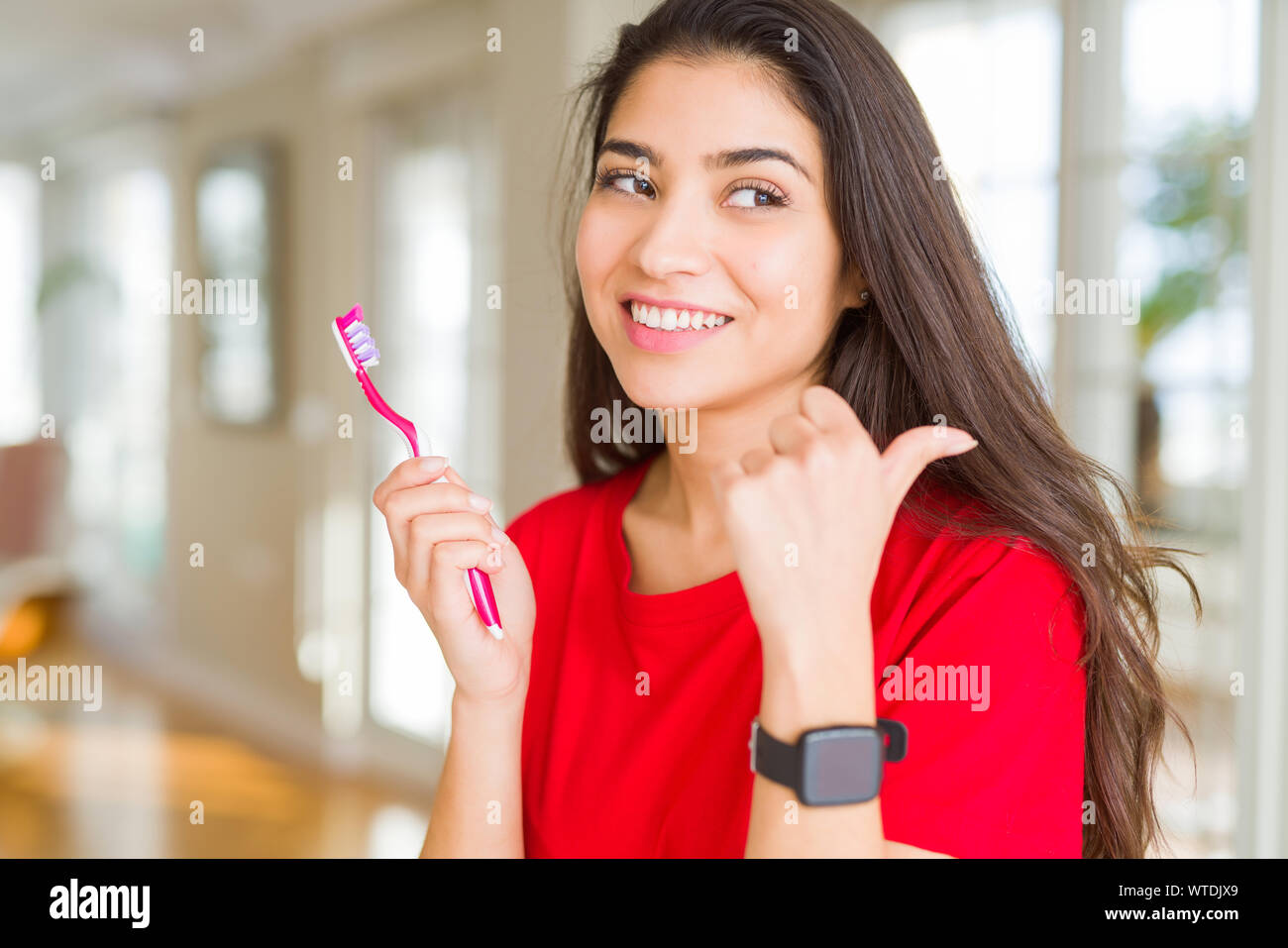 Young woman holding dental toothbrush pointing and showing with thumb ...