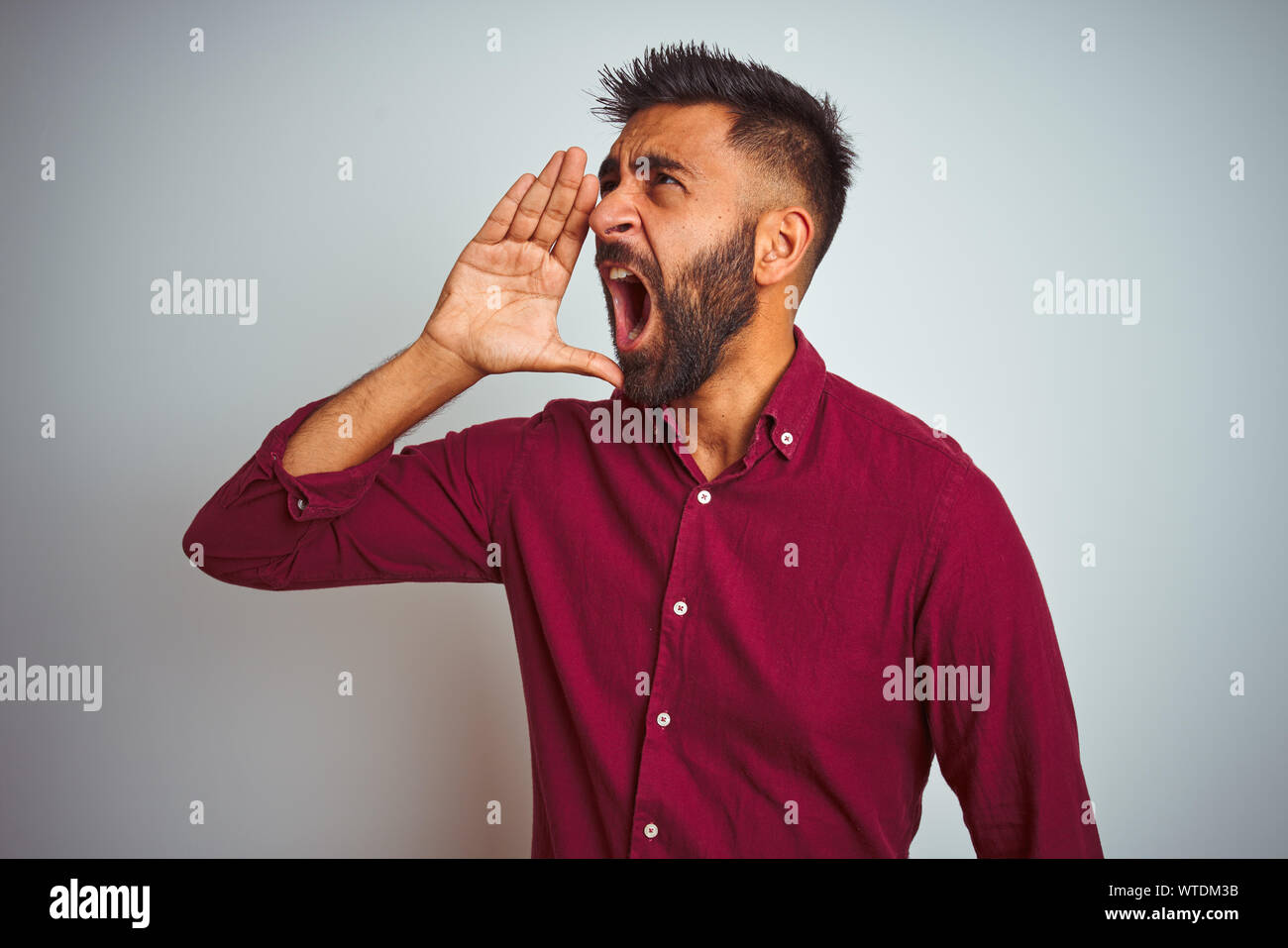 Young indian man wearing red elegant shirt standing over isolated grey ...