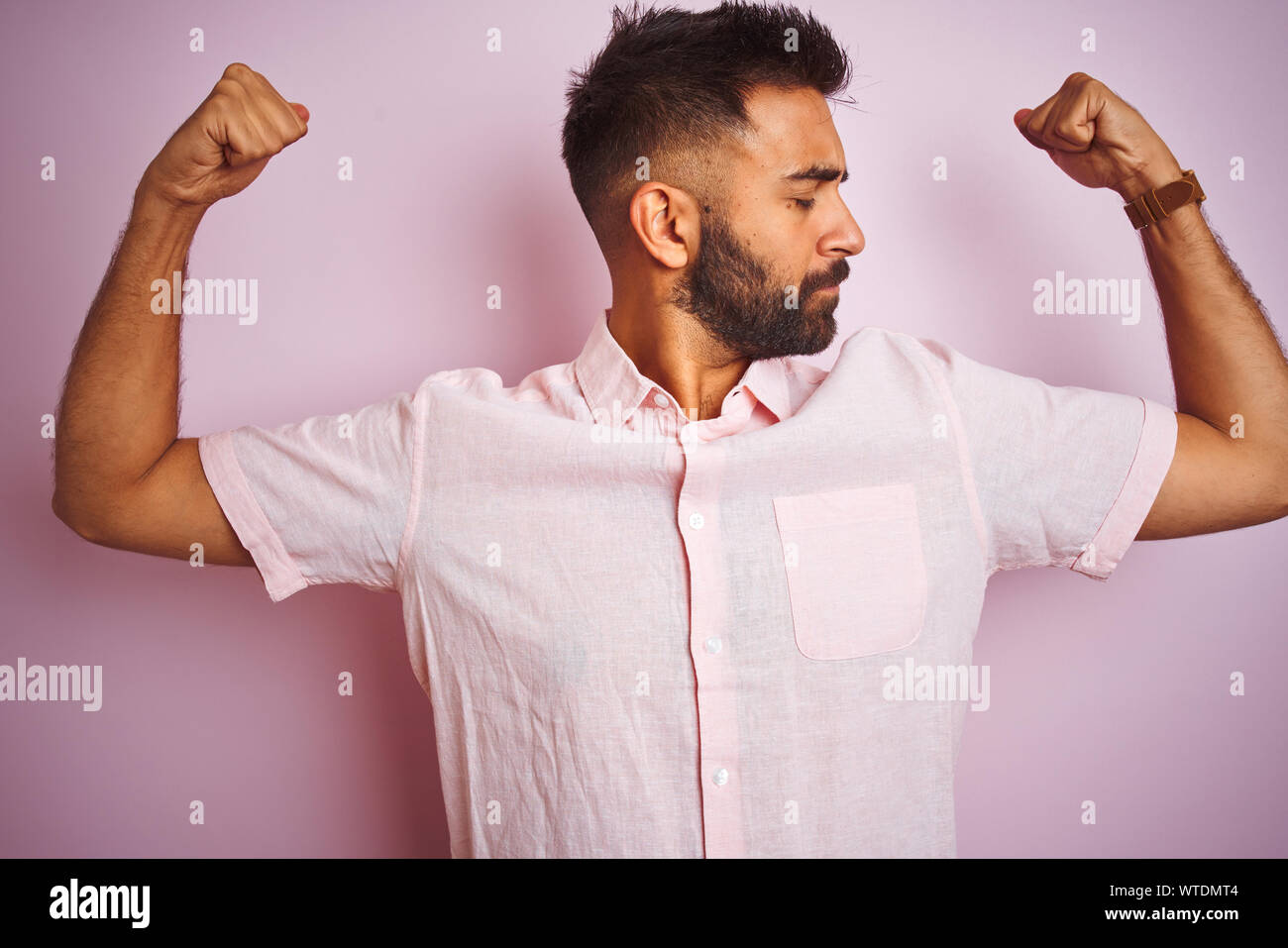 Young indian man wearing casual shirt standing over isolated pink ...