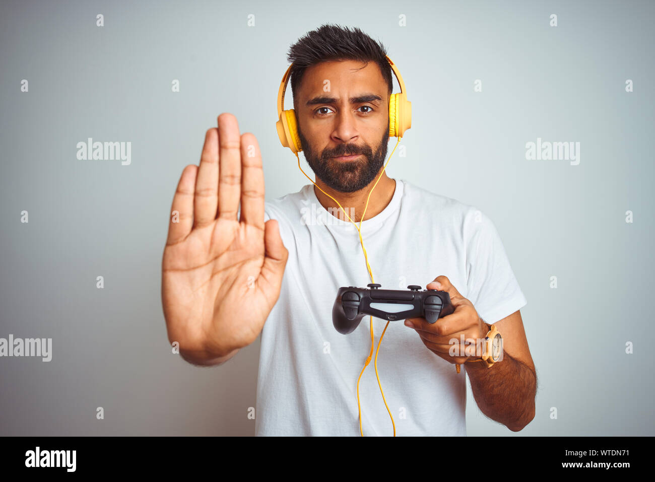 Arab indian gamer man playing video game using headphones over isolated ...
