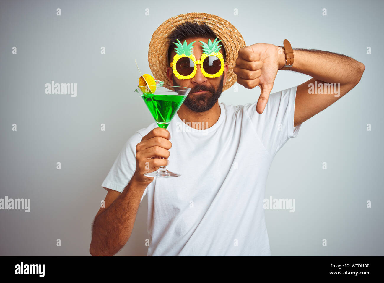 Indian man wearing summer funny look drinking cocktail over isolated ...