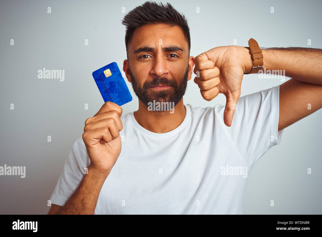 Young indian customer man holding credit card standing over isolated ...