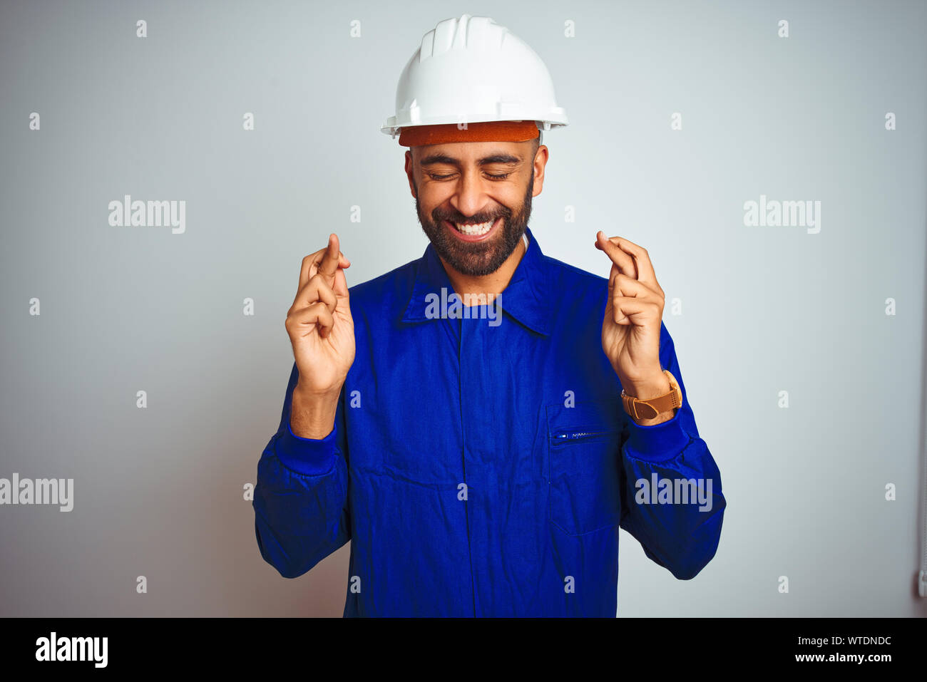Handsome indian worker man wearing uniform and helmet over isolated ...