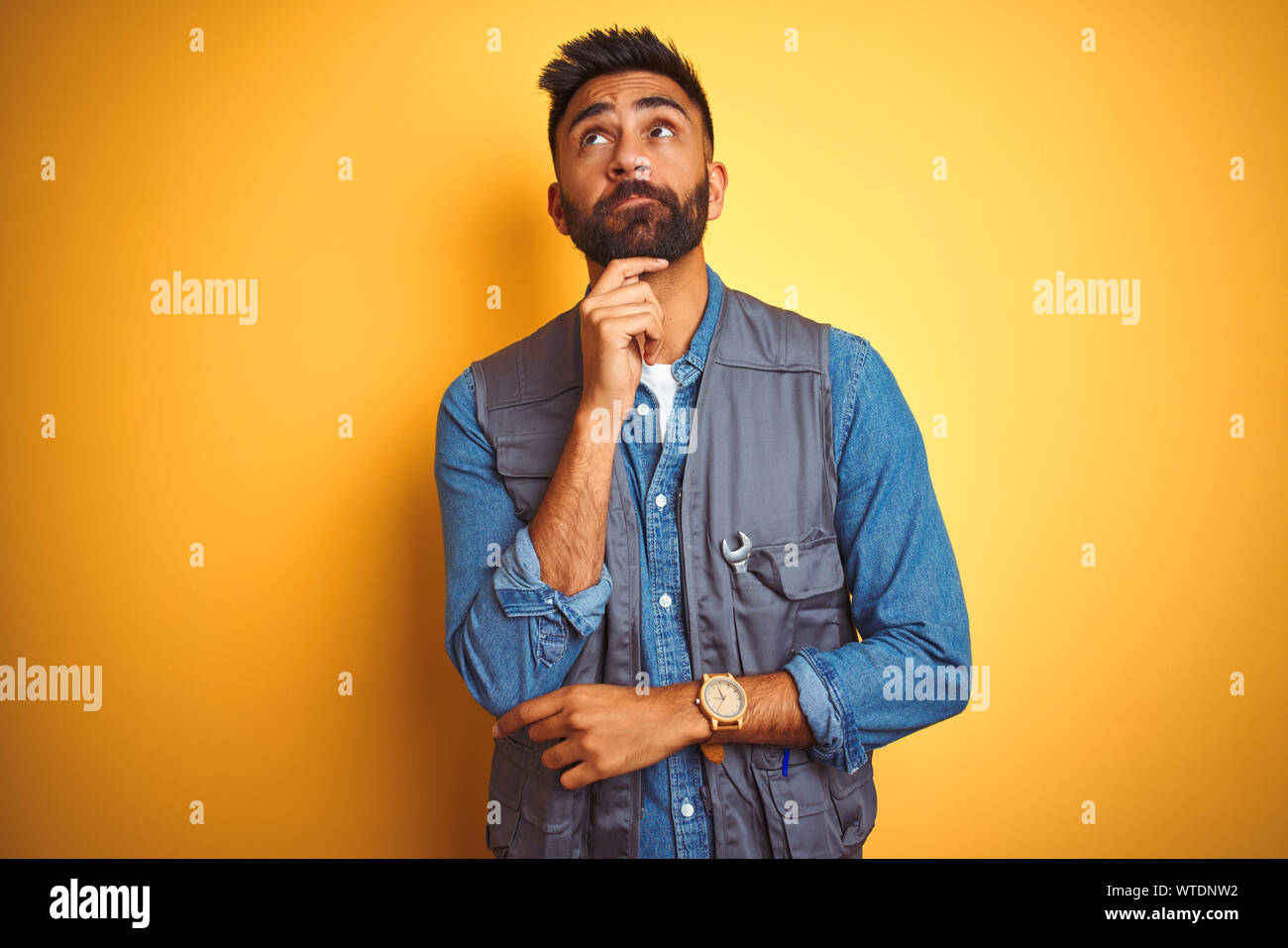 Handsome indian technician man wearing uniform over isolated yellow ...