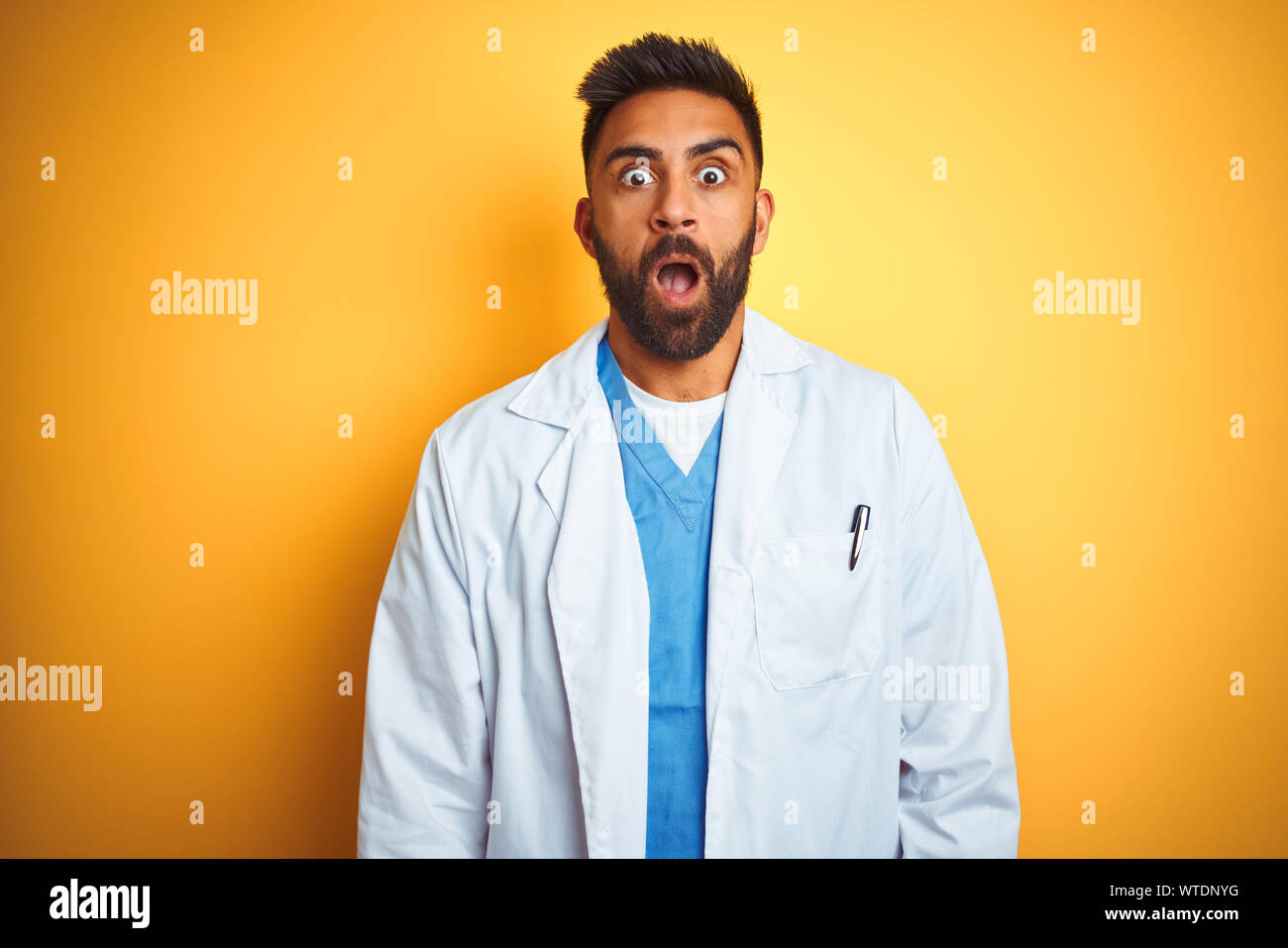 Young indian doctor man standing over isolated yellow background afraid ...