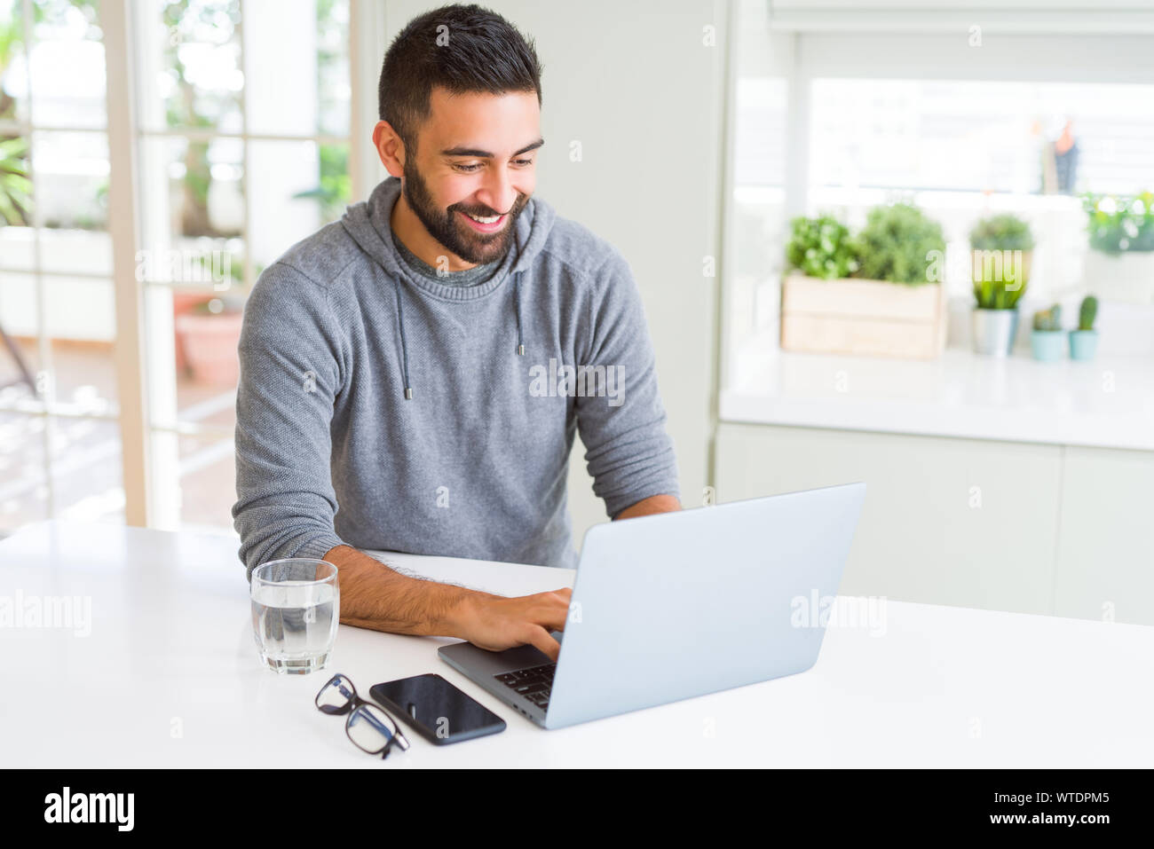 Handsome hispanic man working using computer laptop with a happy face ...