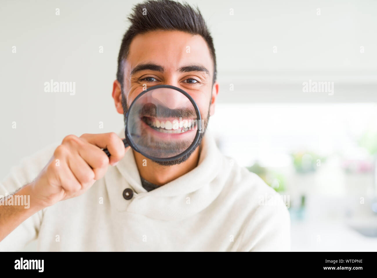 Handsome man using magnifying glass, doing funny faces Stock Photo - Alamy