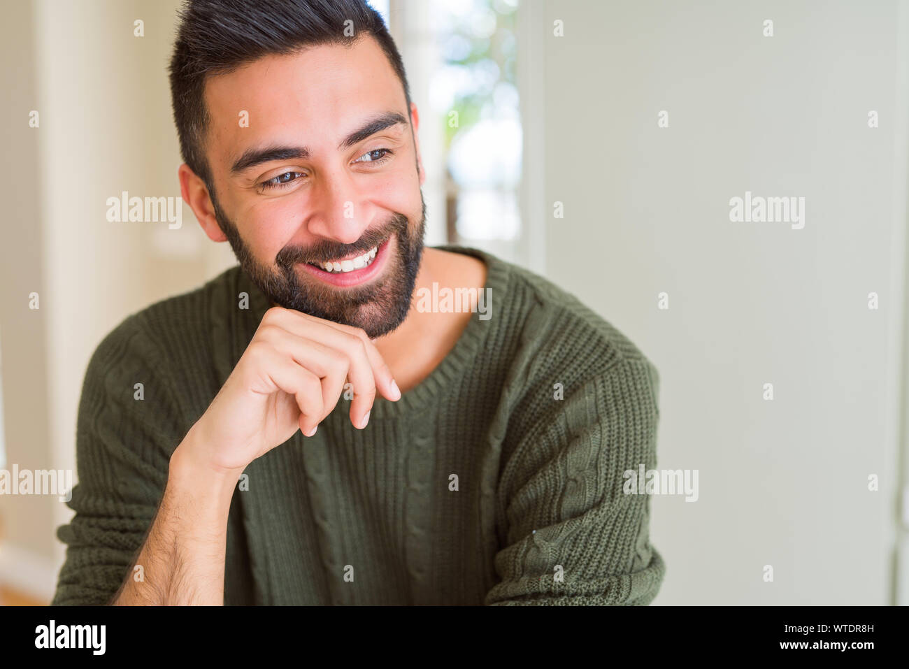 Handsome man thinking confused about doubt, questioning an idea smiling ...